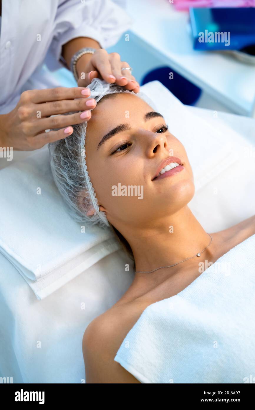 Cosmetologist preparing client for cosmetic procedures by putting ...