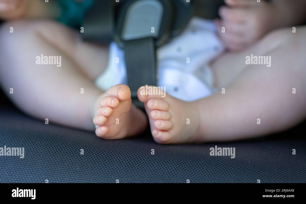An infant with bared feet sitting on the chair Stock Photo - Alamy