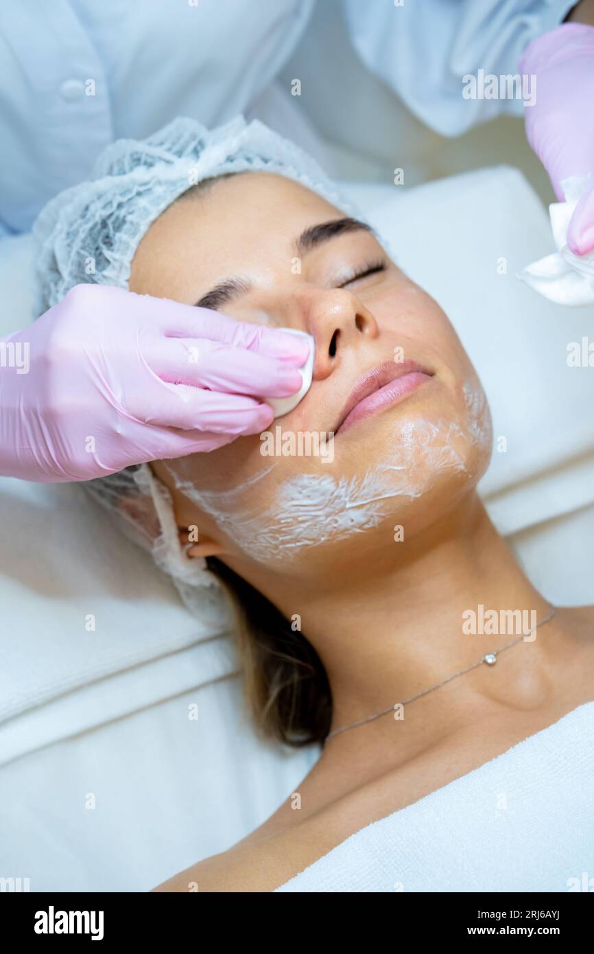 Beautician's hands cleaning female face with cotton pads at aesthetic ...