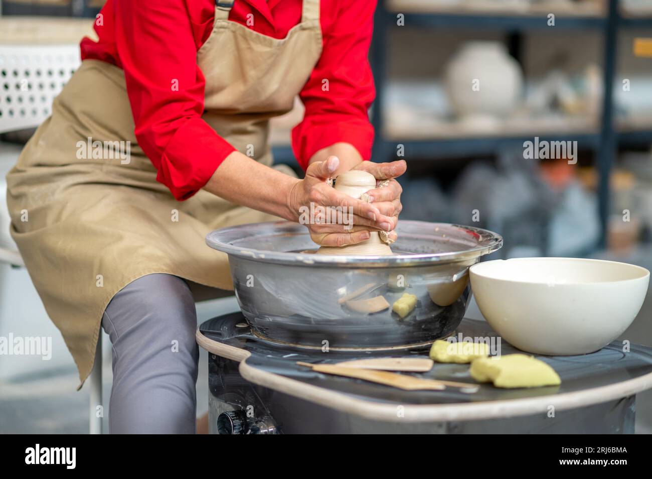 Woman working on potter's wheel in a pottery workshop, creating clay ...