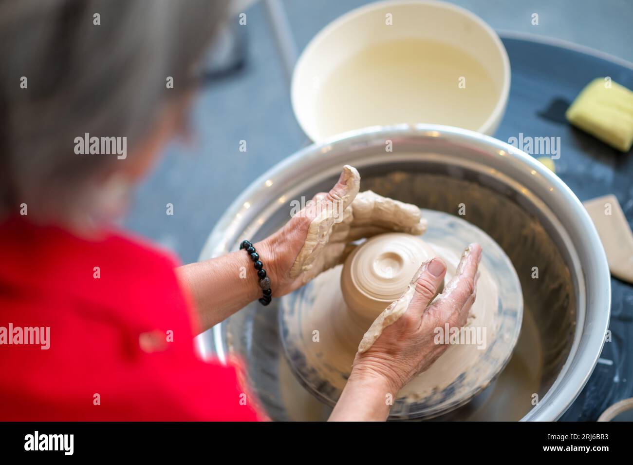 Woman working on potter's wheel in a pottery workshop, creating clay ...
