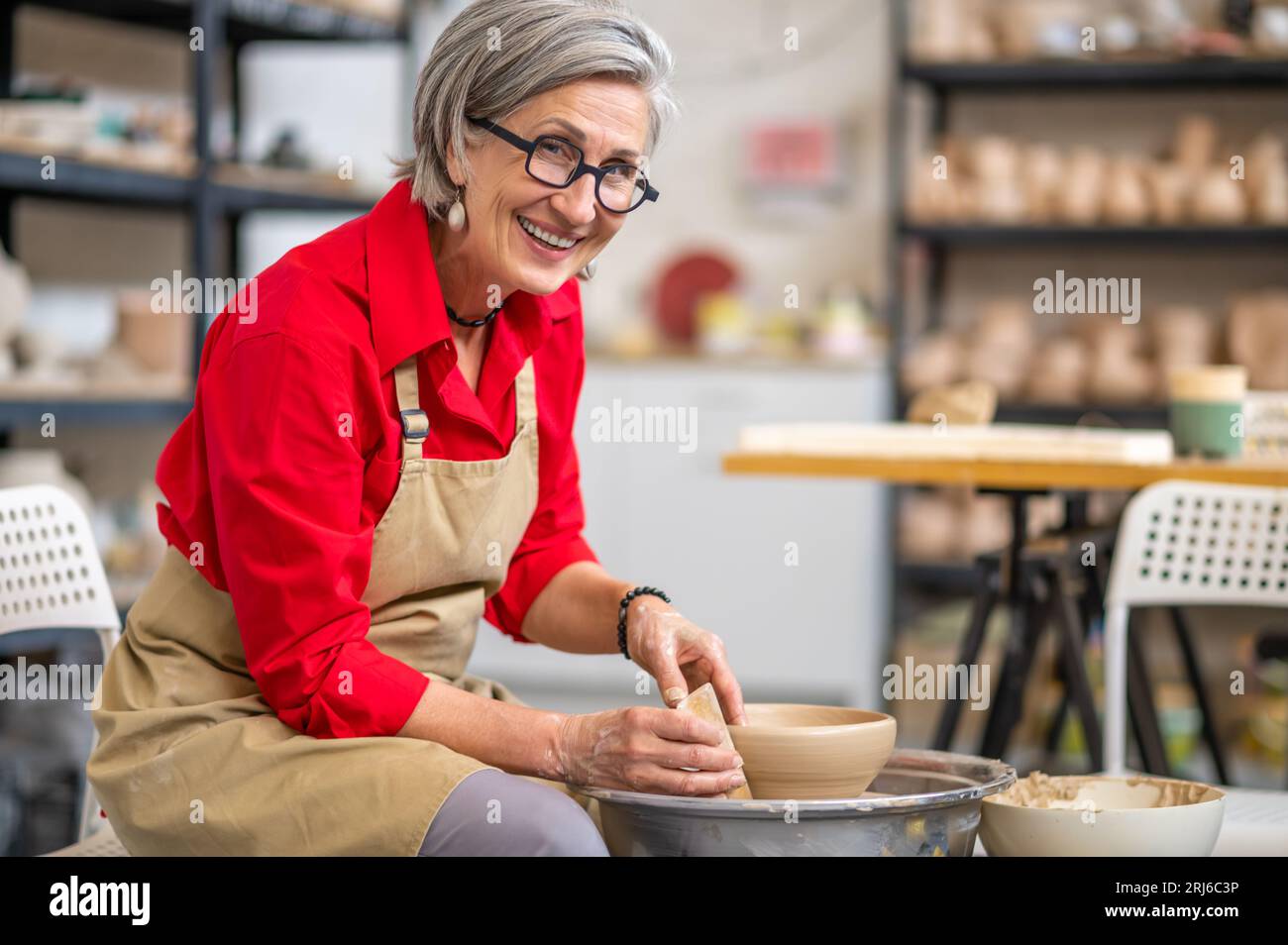 Woman making clay plate on a potter's wheel in the handcraft workshop ...