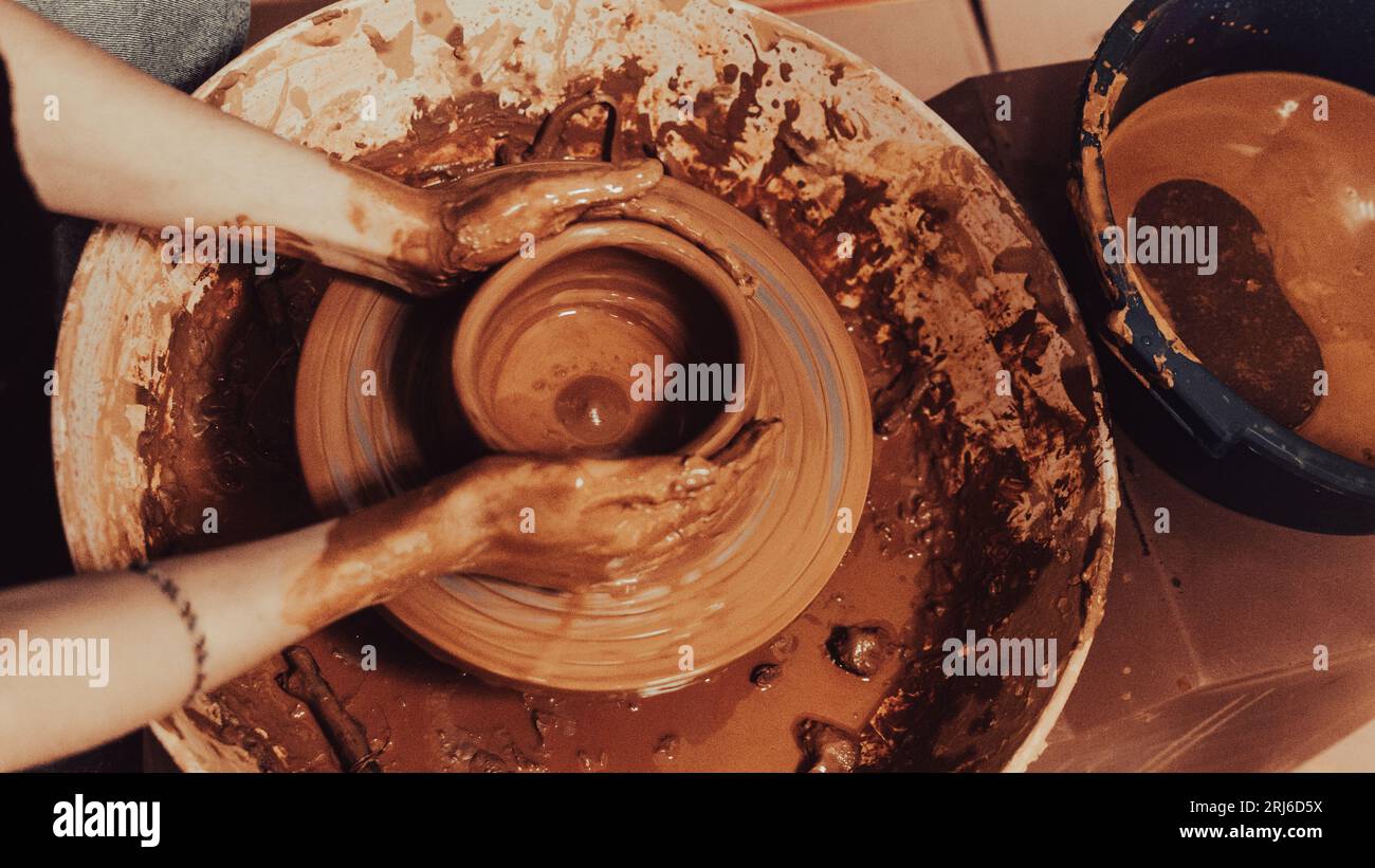 A person shaping a bowl of clay with their hands Stock Photo - Alamy