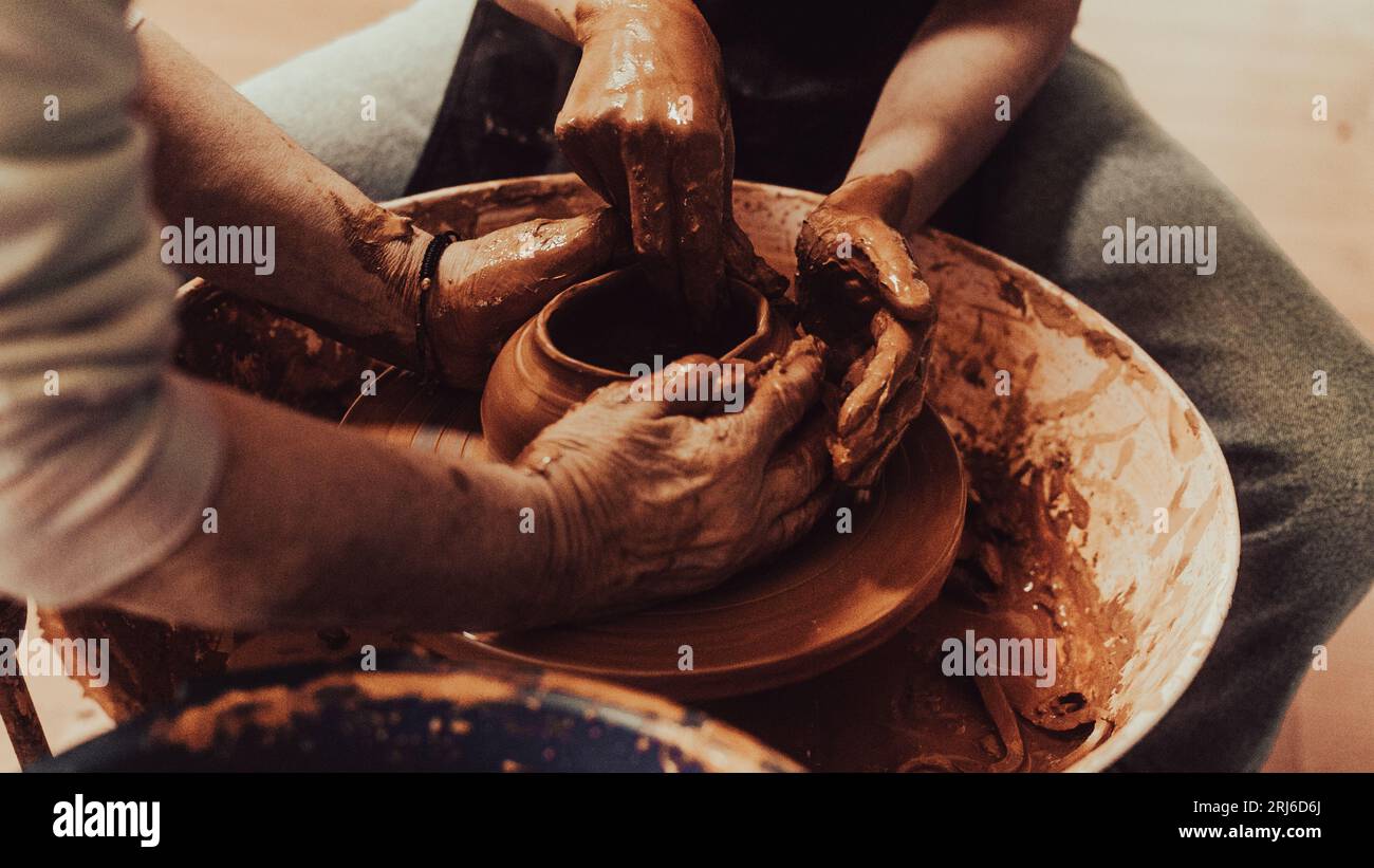 A person shaping a bowl of clay with their hands Stock Photo - Alamy