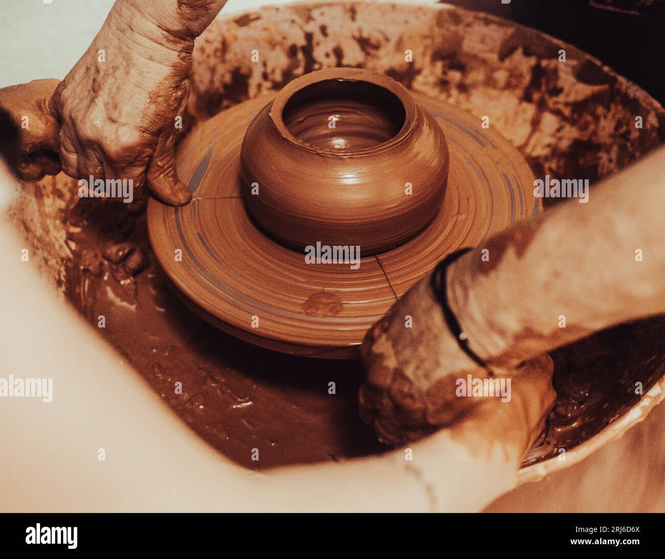 A person shaping a bowl of clay with their hands Stock Photo - Alamy