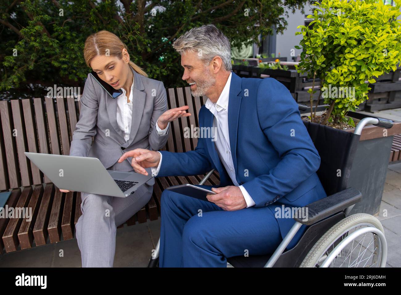Businessman in wheelchair with female partner woman talking phone using ...