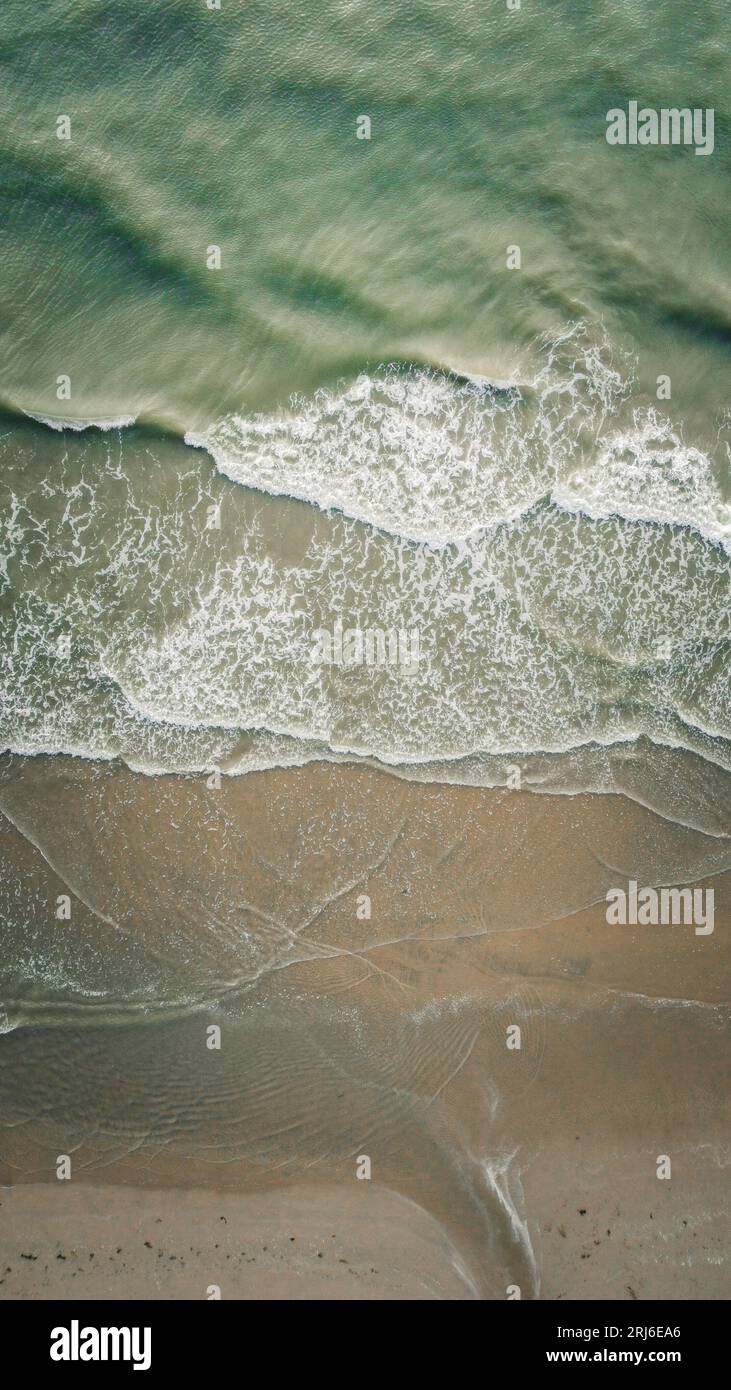 An aerial view of a stunning sandy beach with beautiful blue rolling ...