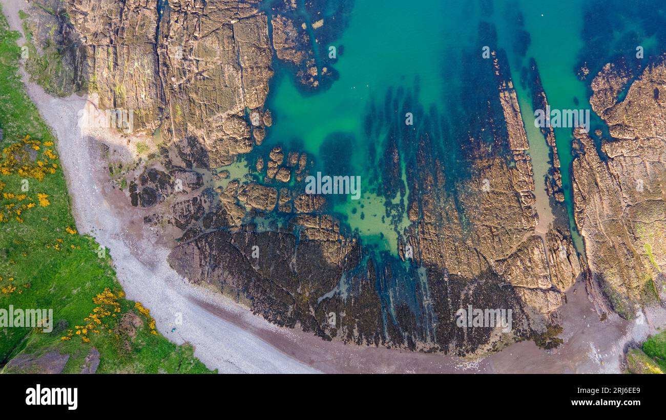 An aerial view of a majestic rocky cliff overlooks a serene blue lake ...