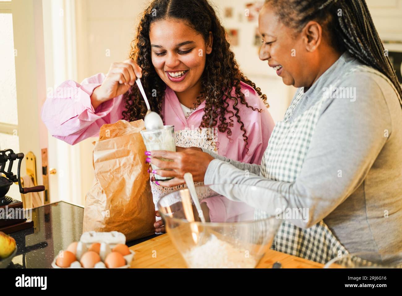 African mother and daughter preparing yogurt gluten free cake at home ...