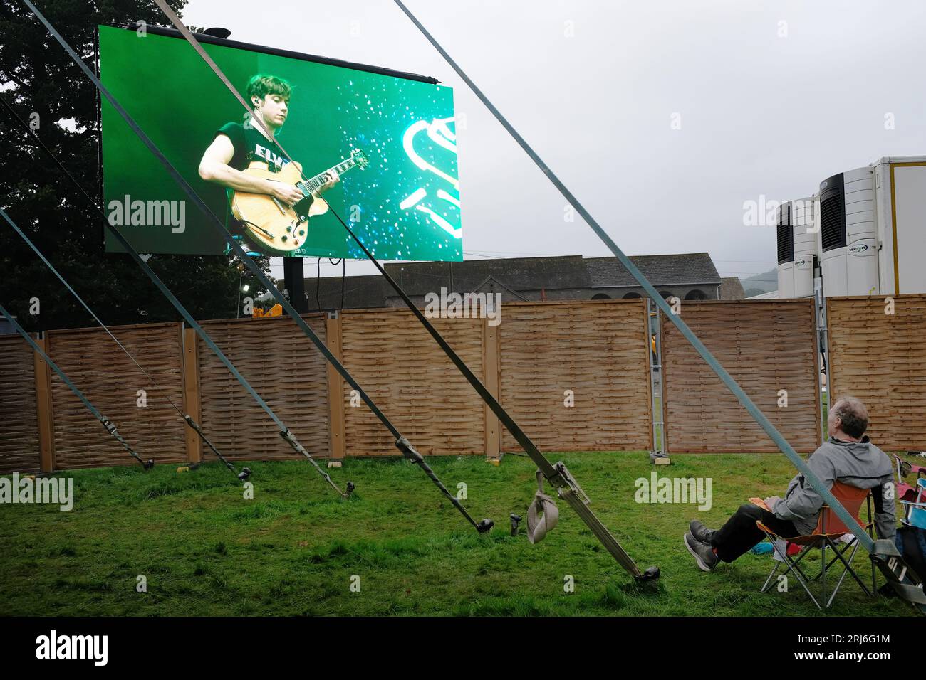 A man watching a band on a screen at the Greenman festival on his own ...