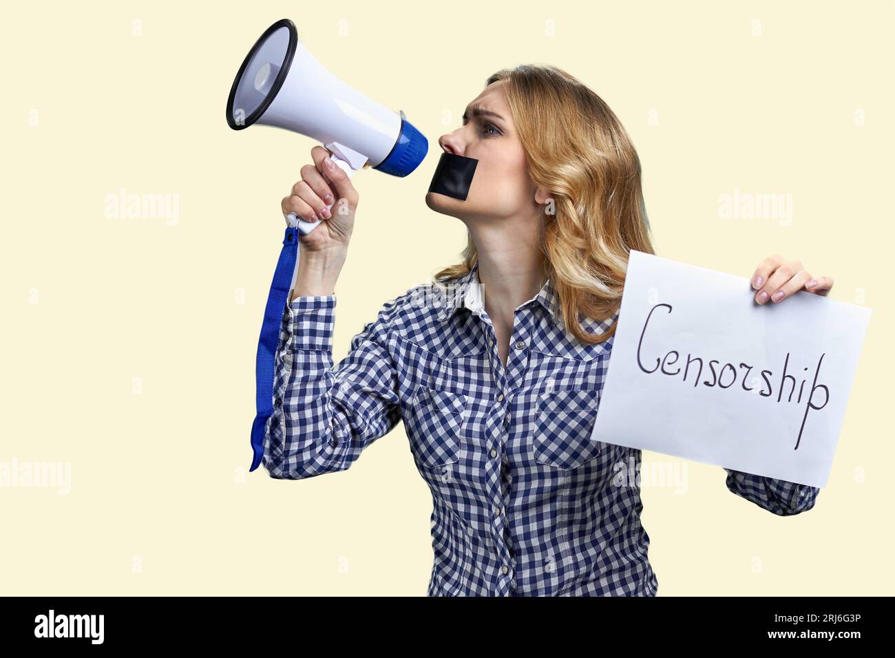 Young blonde woman with taped mouth holding megaphone and banner with ...