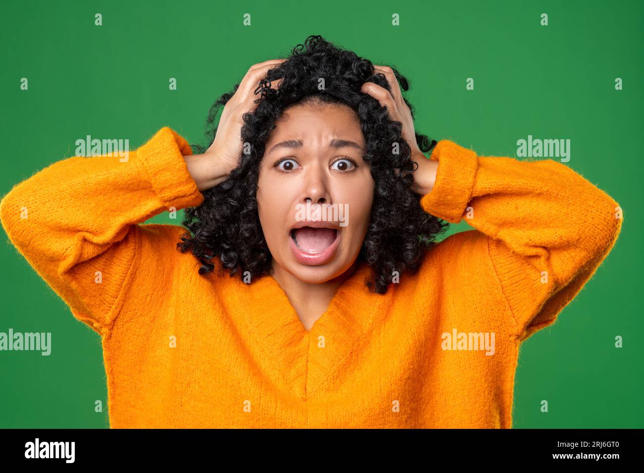 Dark-haired woman in orange looking stressed and shocked Stock Photo ...