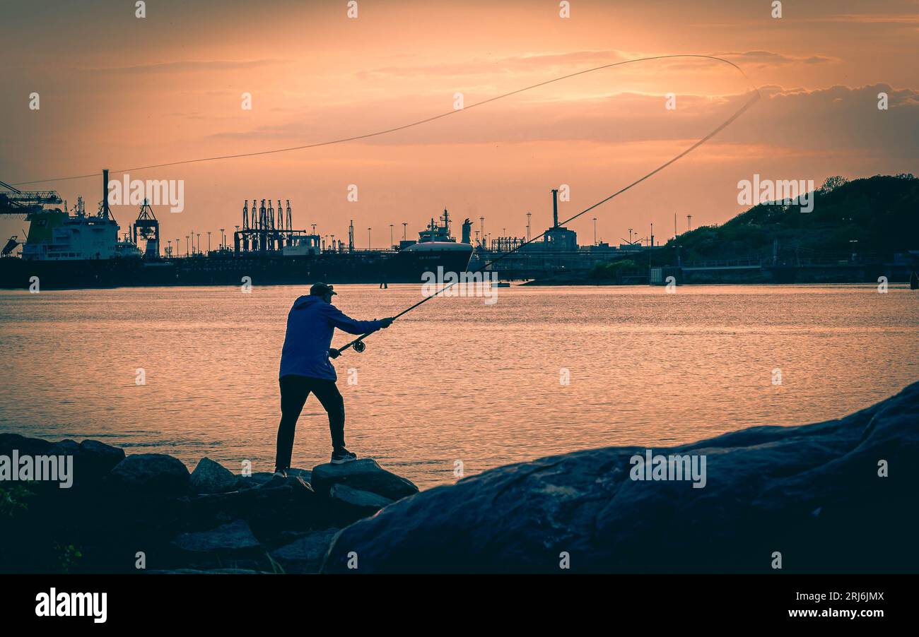 Silhouetted figure enjoying a peaceful sunset, standing at the edge of ...