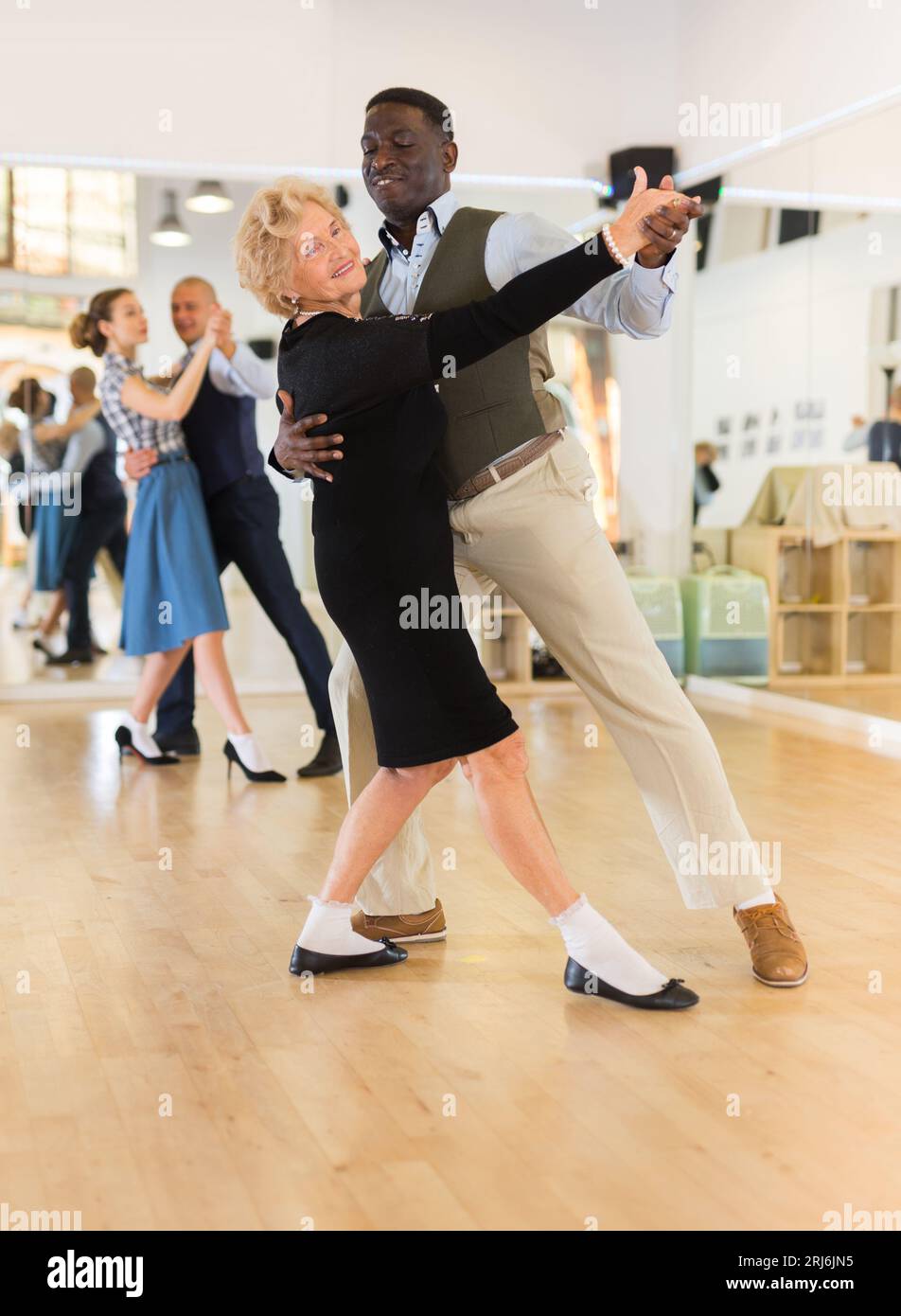 Man and elderly woman performing ballroom dance in dancing room Stock ...