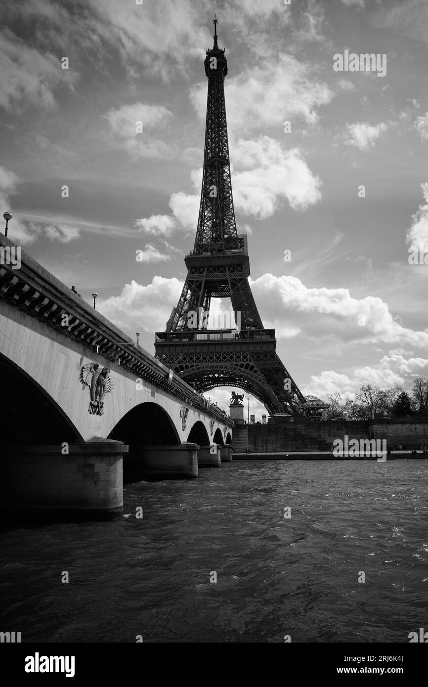 A grayscale shot of a canal and the Eiffel Tower in the daylight in ...