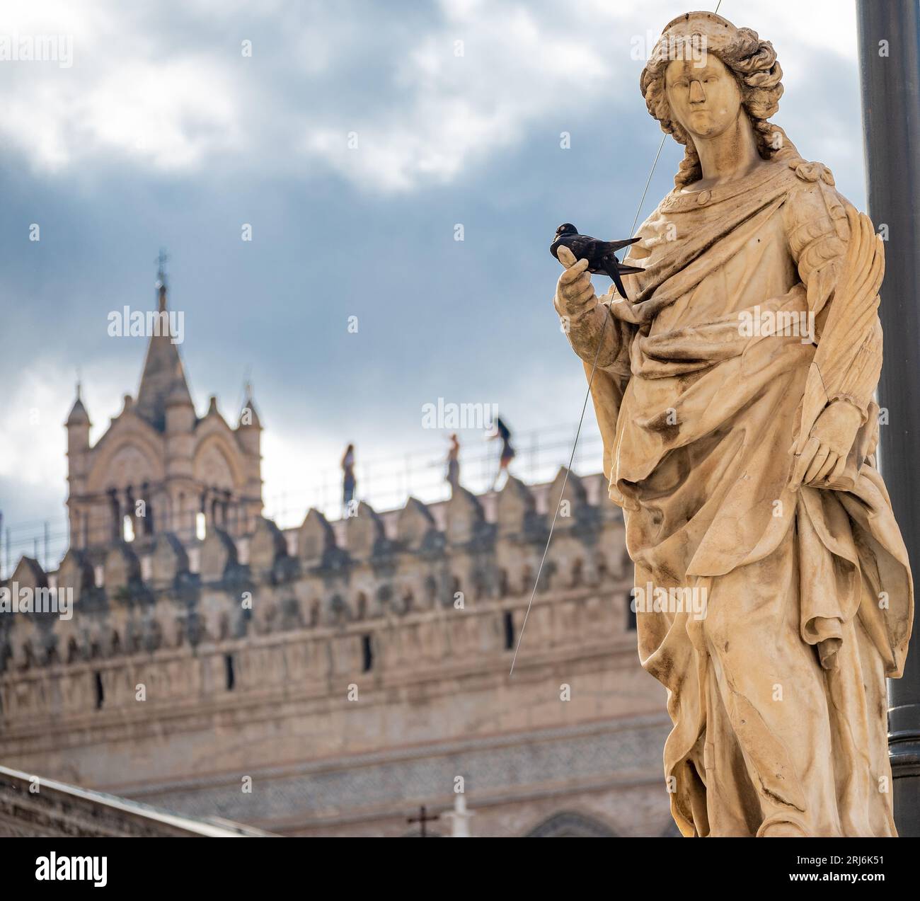 A closeup of a vintage-style statue of a man with a small bird perched ...