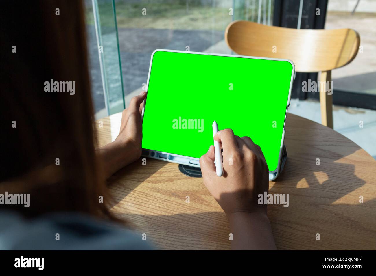 A female adult is using a modern tablet with a bright green screen ...