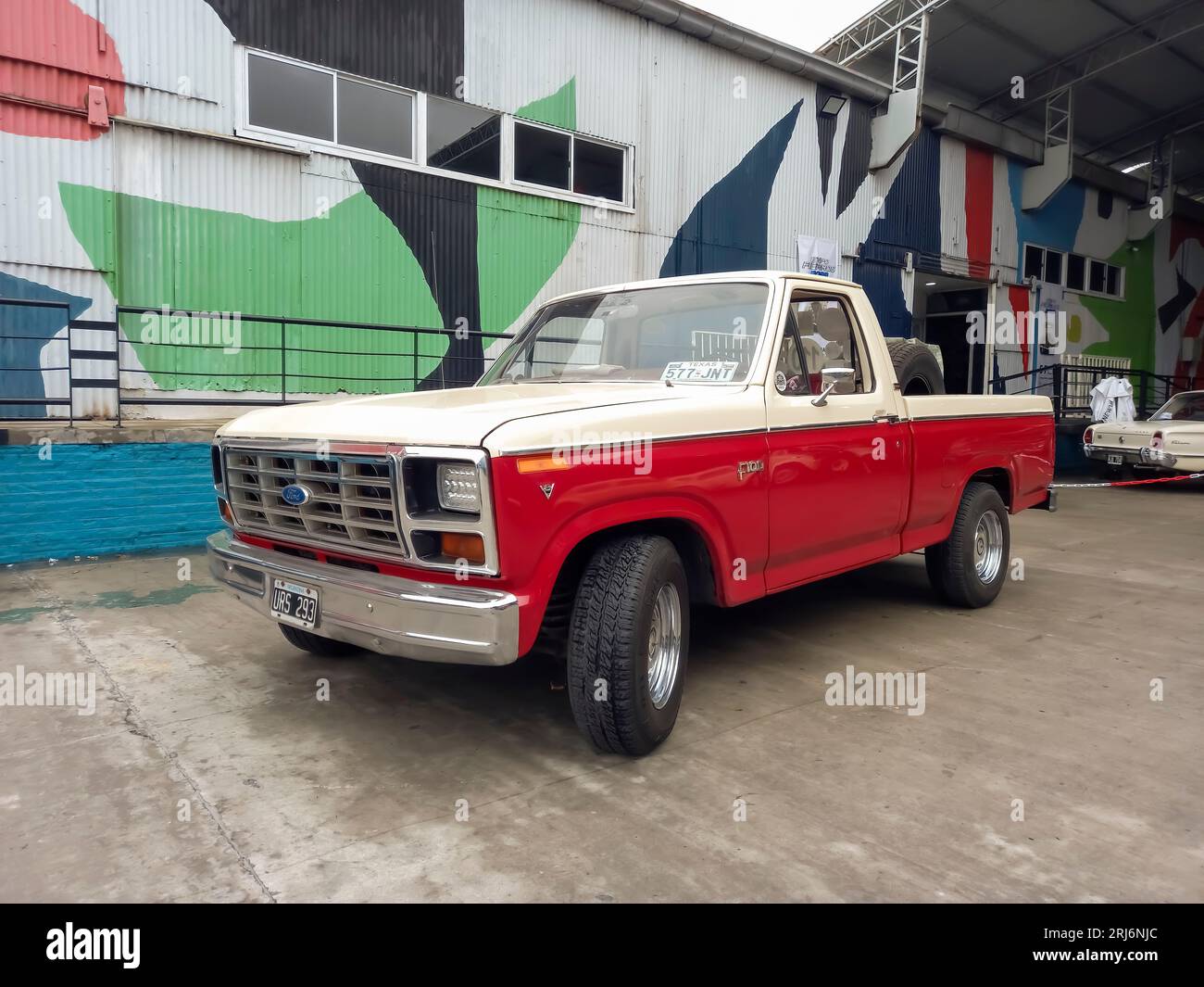 Old red and white 1980s Ford F 100 V8 pickup truck on a colorful ...