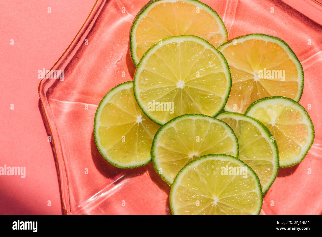 bright green sliced lime wheels on pink glass plate, background Stock ...