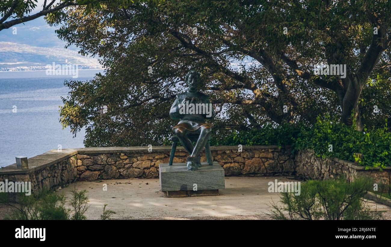 An outdoor statue of a sailor in a park setting, surrounded by trees ...