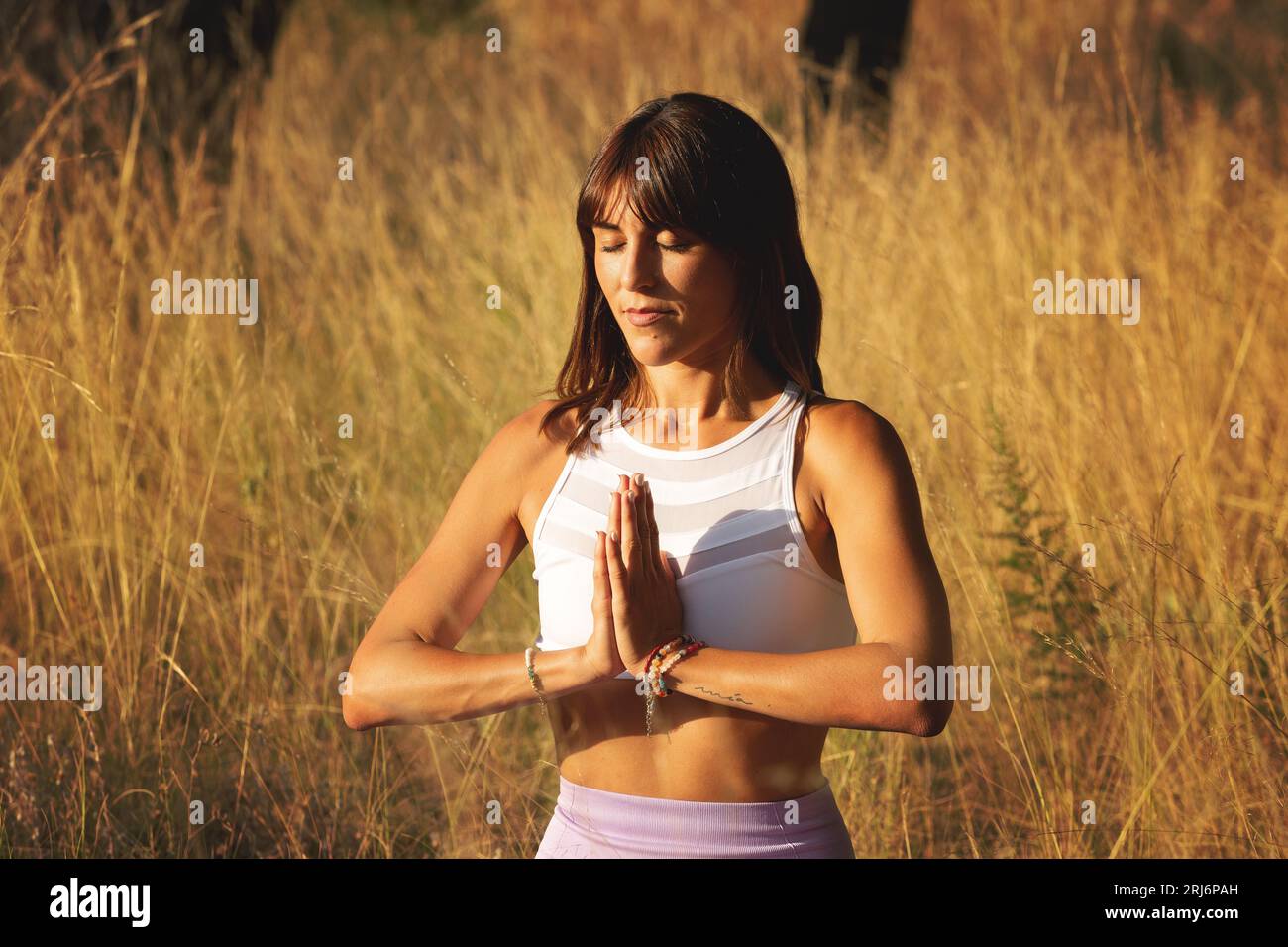 A woman performing yoga poses in a field of tall grass Stock Photo - Alamy
