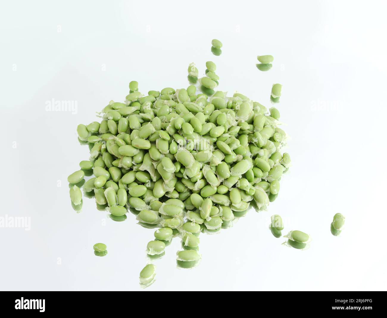 A pile of freshly picked green beans cascading onto a plain white ...