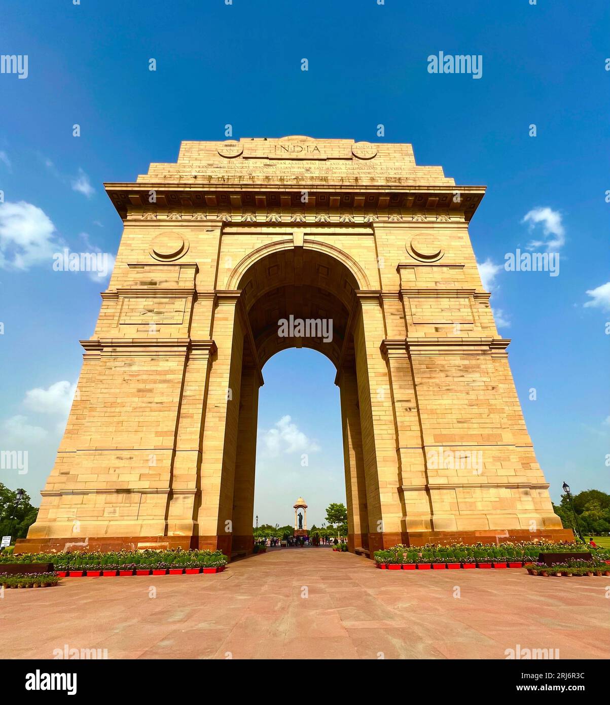 An image of India Gate surrounded by lush greenery and a bright blue ...