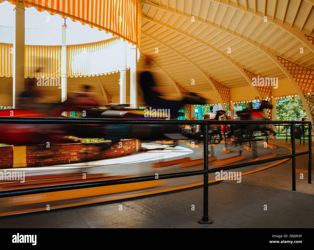 A vibrant, colorful carousel in a park setting, illuminated in a soft ...
