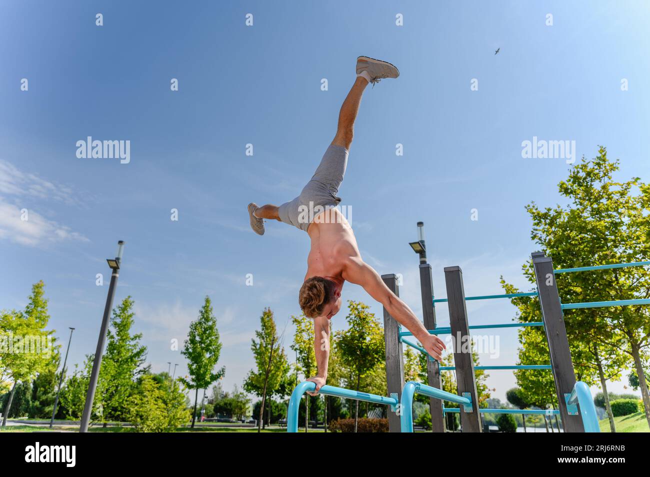Man doing hand stand push ups exercise in parallel bars. Outdoor sports ...