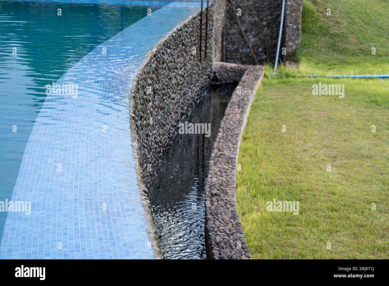 The edge of an infinity pool, draining over a ledge. Resort swimming ...