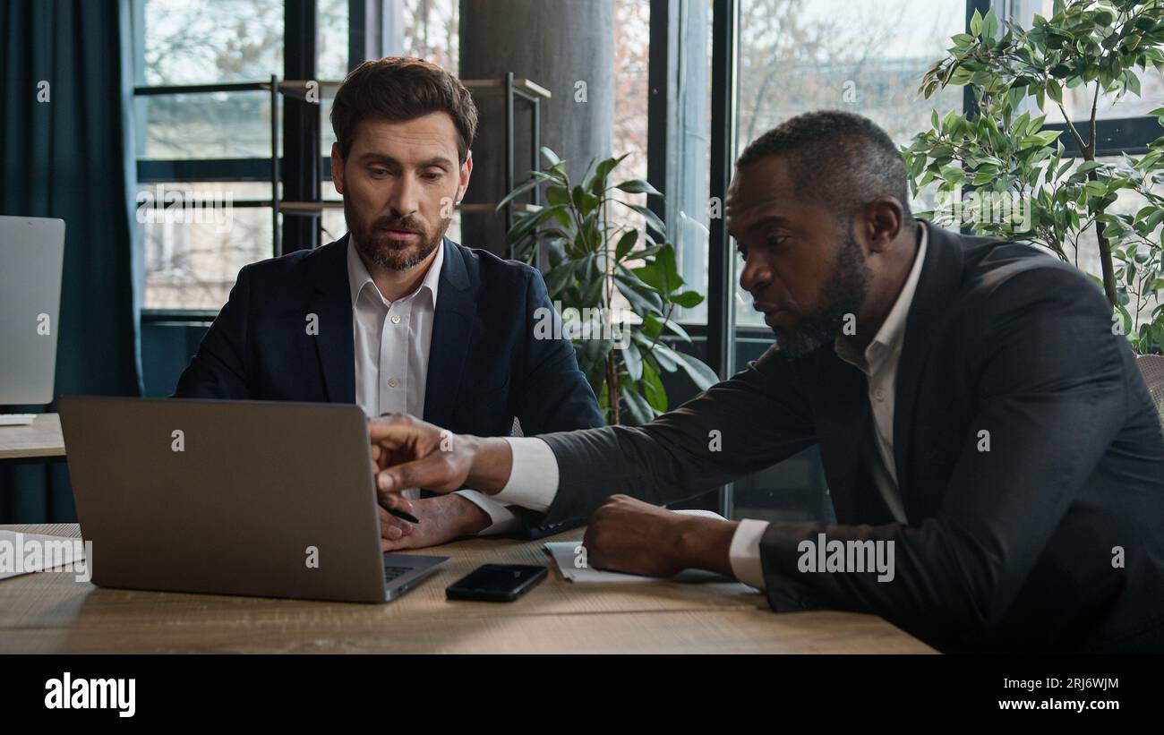Two diverse multiracial businessmen discuss online data project with ...