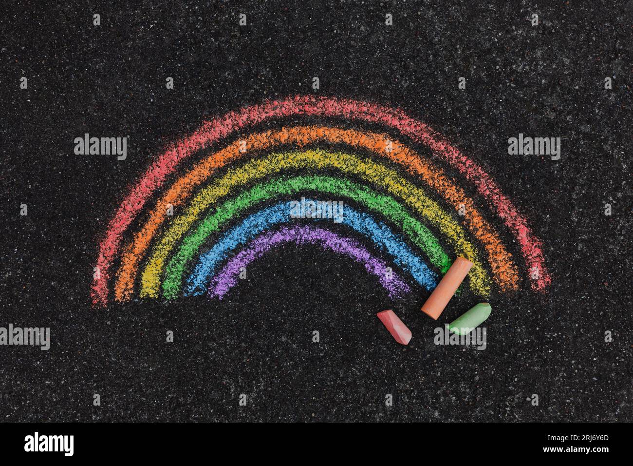 Close-up of a colorful rainbow painted on a road with sidewalk chalk ...