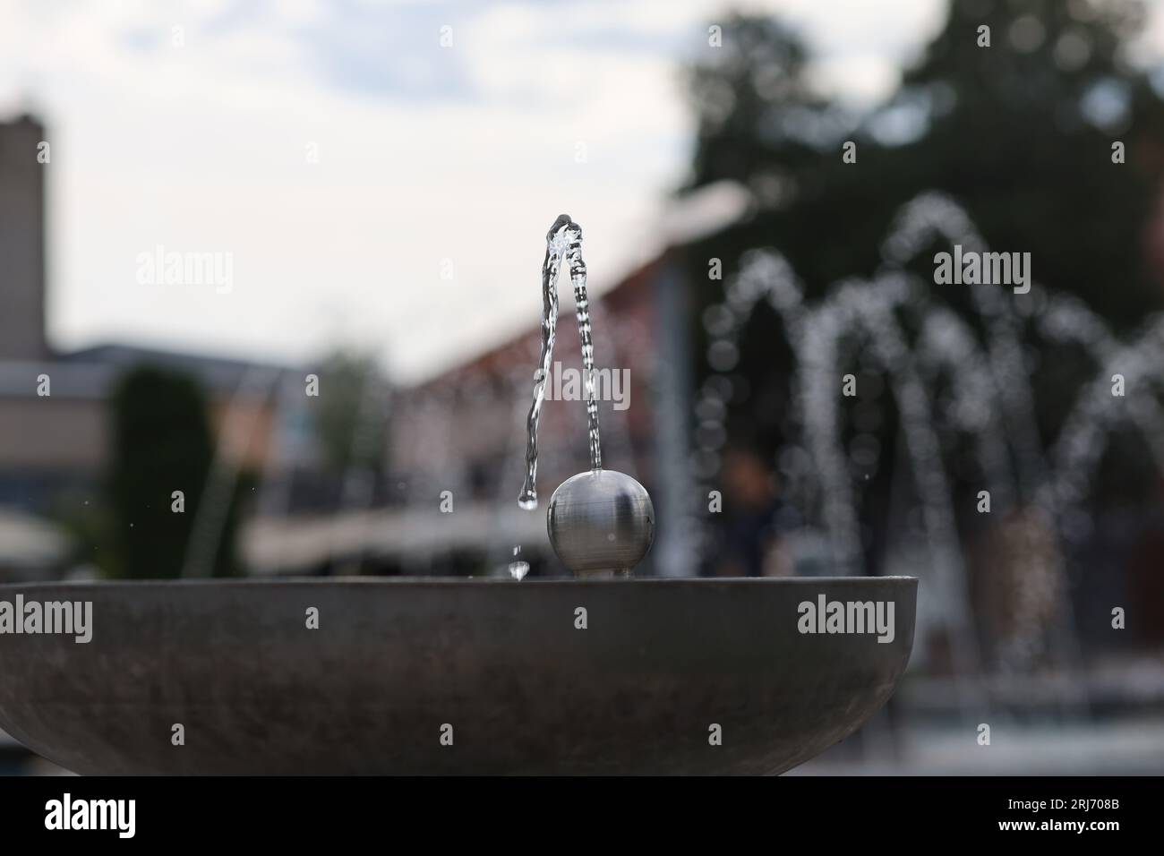 A tranquil fountain in a bustling cityscape, featuring water cascading ...