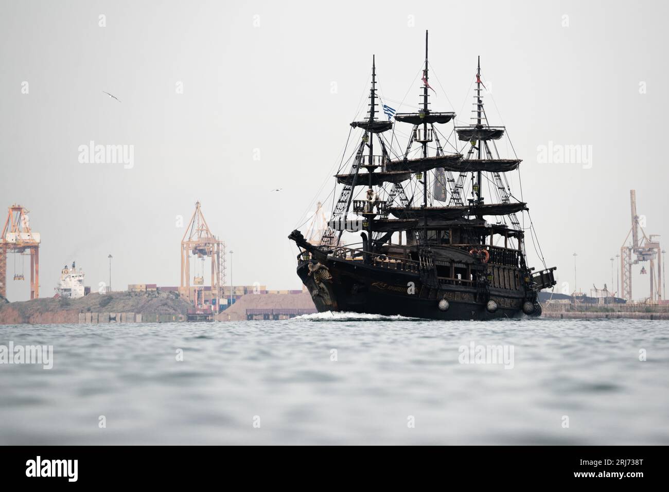 A black pirate ship with harbor cranes in the background Stock Photo ...