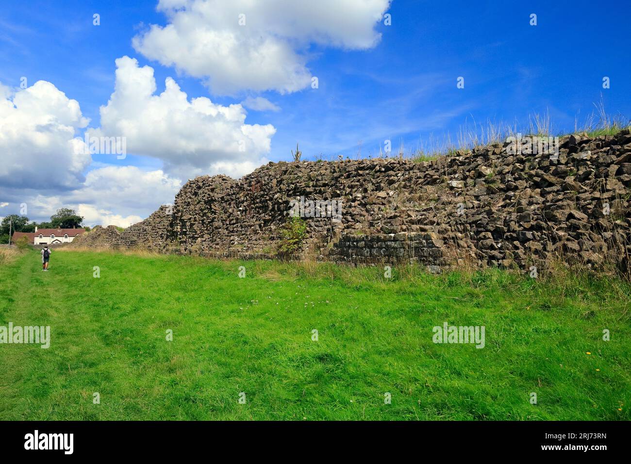 Walker on path alongside well preserved and impressive Roman walls ...
