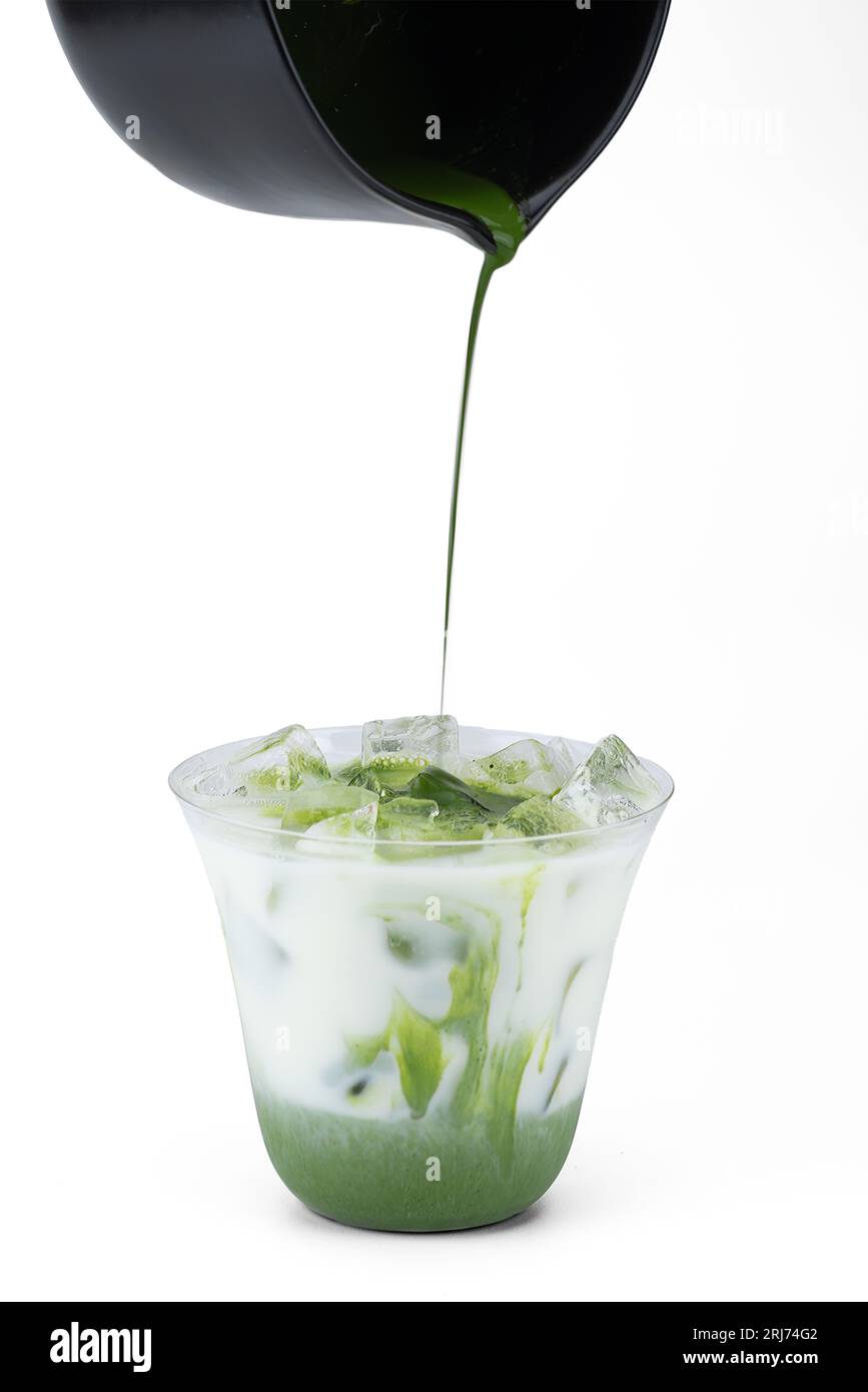 Pouring matcha into cup with ice and milk on a white background ...