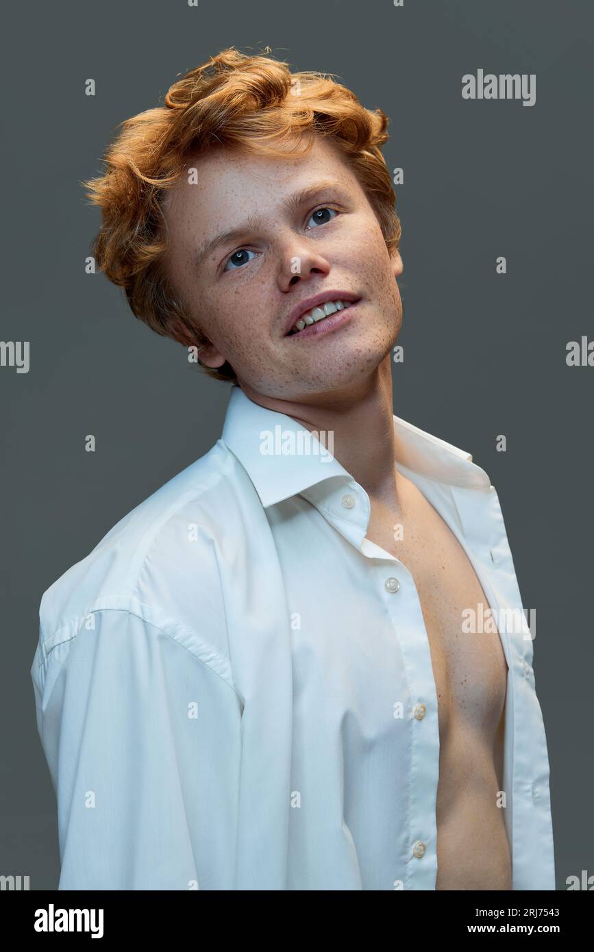 Portrait of attractive young red haired man with freckles in white ...