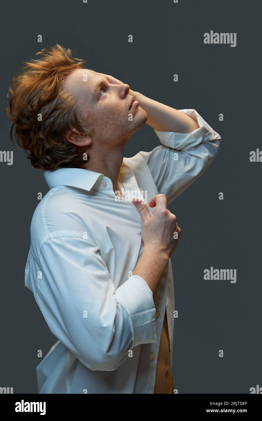 Portrait of attractive young red haired man in white unbuttoned shirt ...