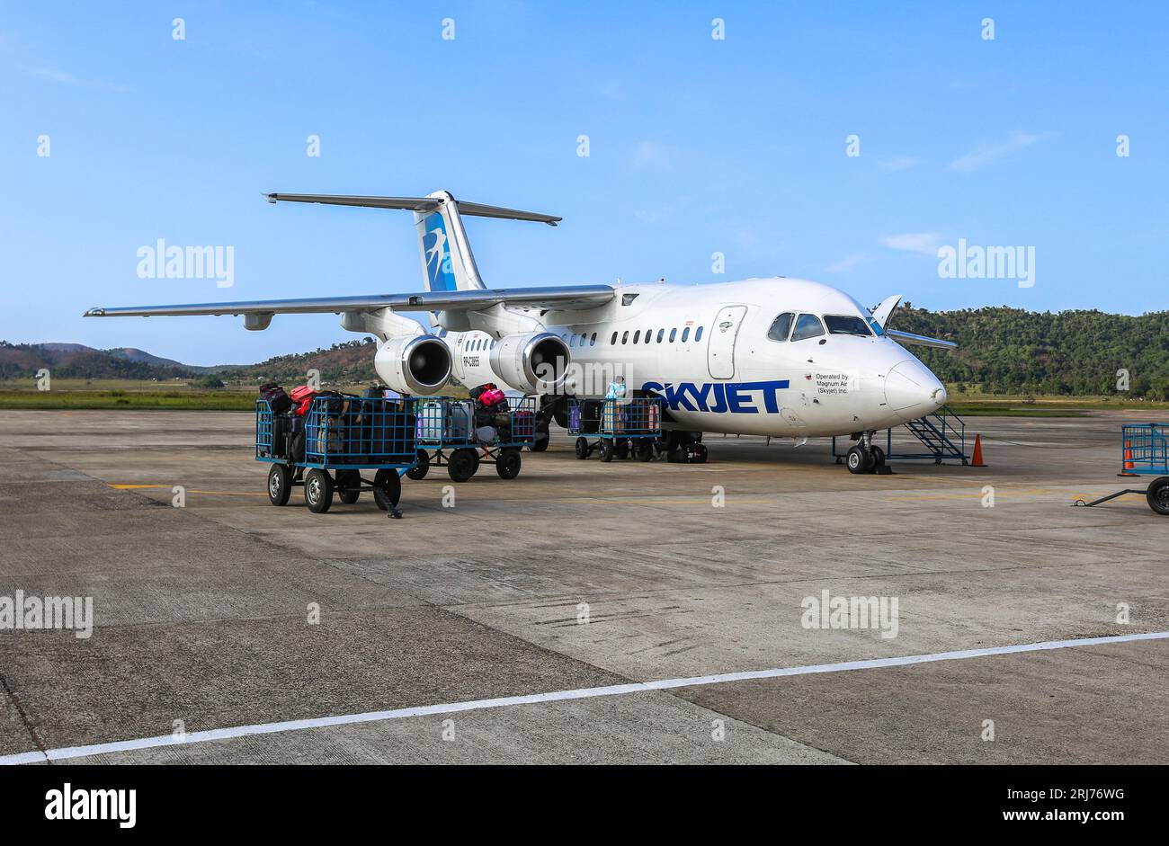 Philippines Skyjet Airlines airplane on the tarmac of Coron small airport, luggage in trolleys ...