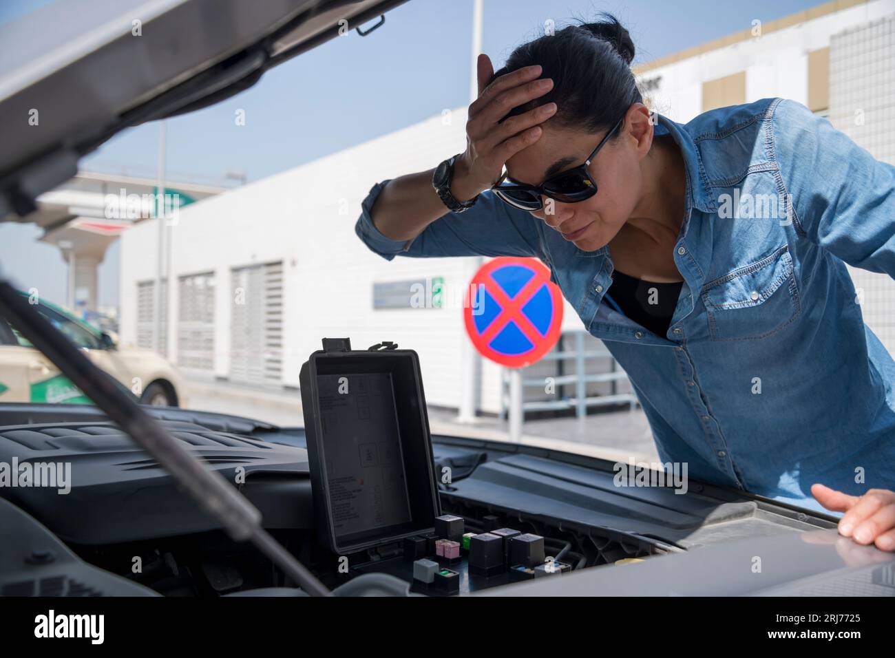 Concerned woman checking car fuses, struggling with a broken-down ...