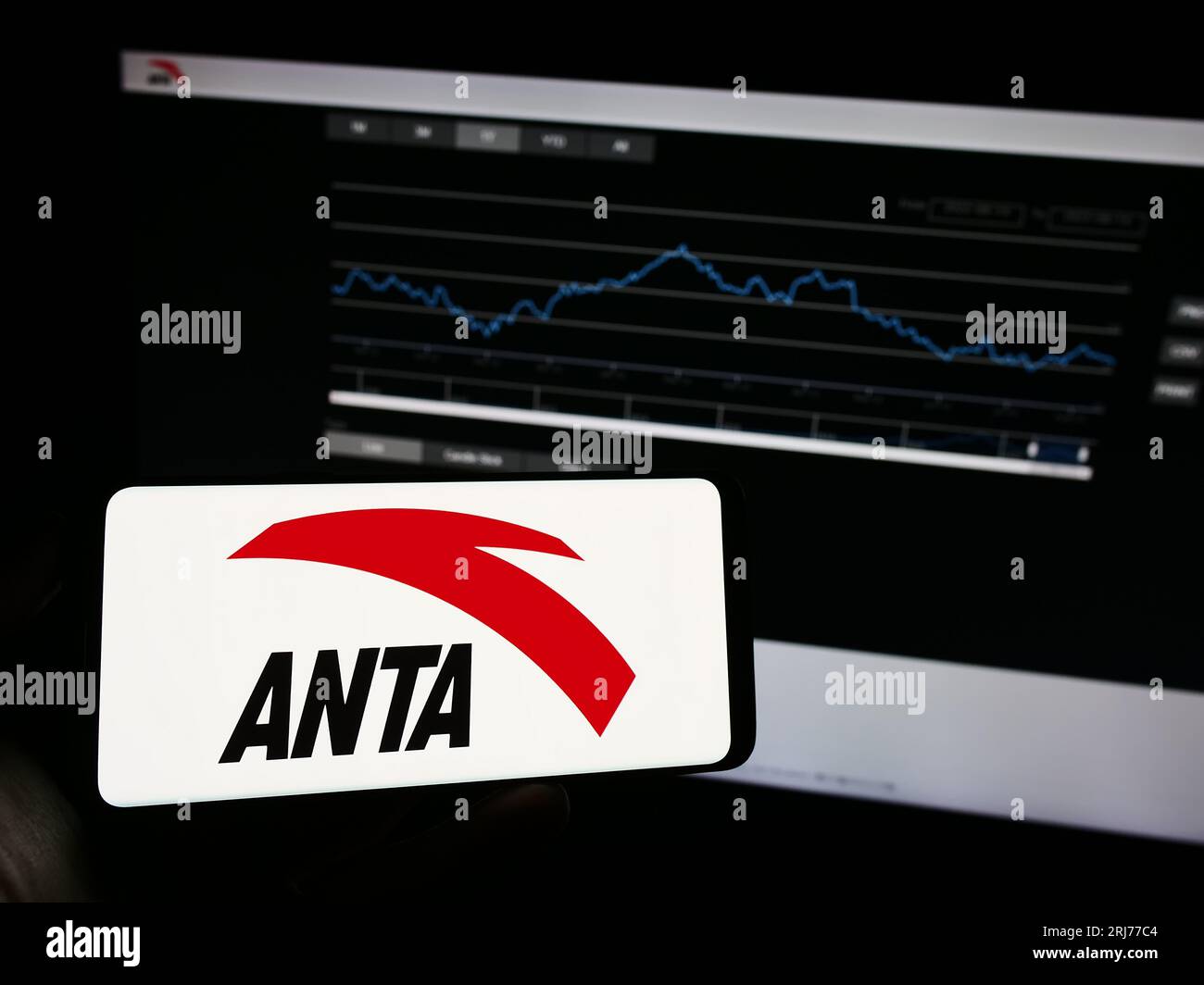 Person holding mobile phone with logo of Chinese company Anta Sports ...