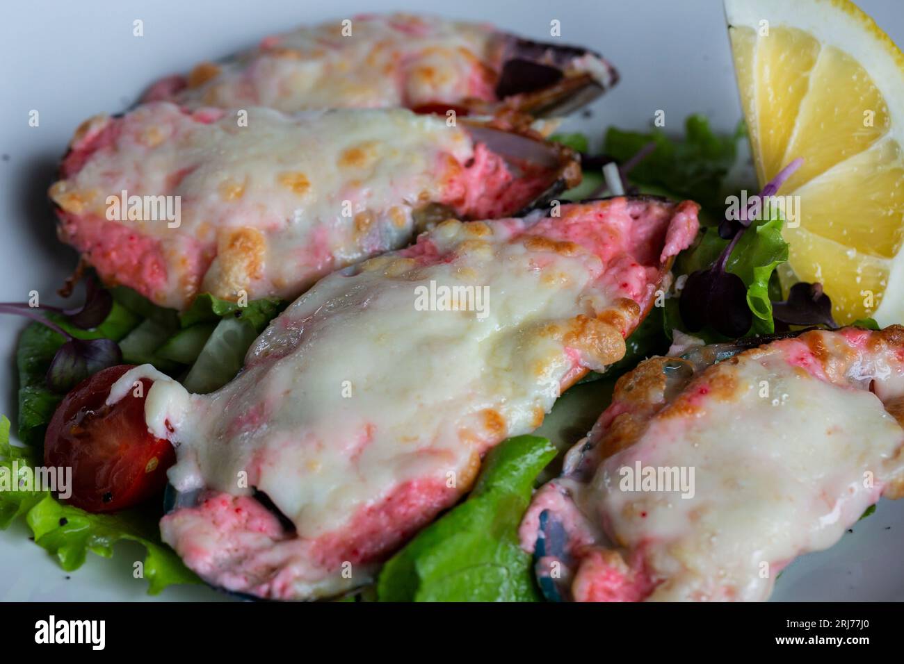 baked mussels with masago caviar and cheese on a white plate whit lemon ...