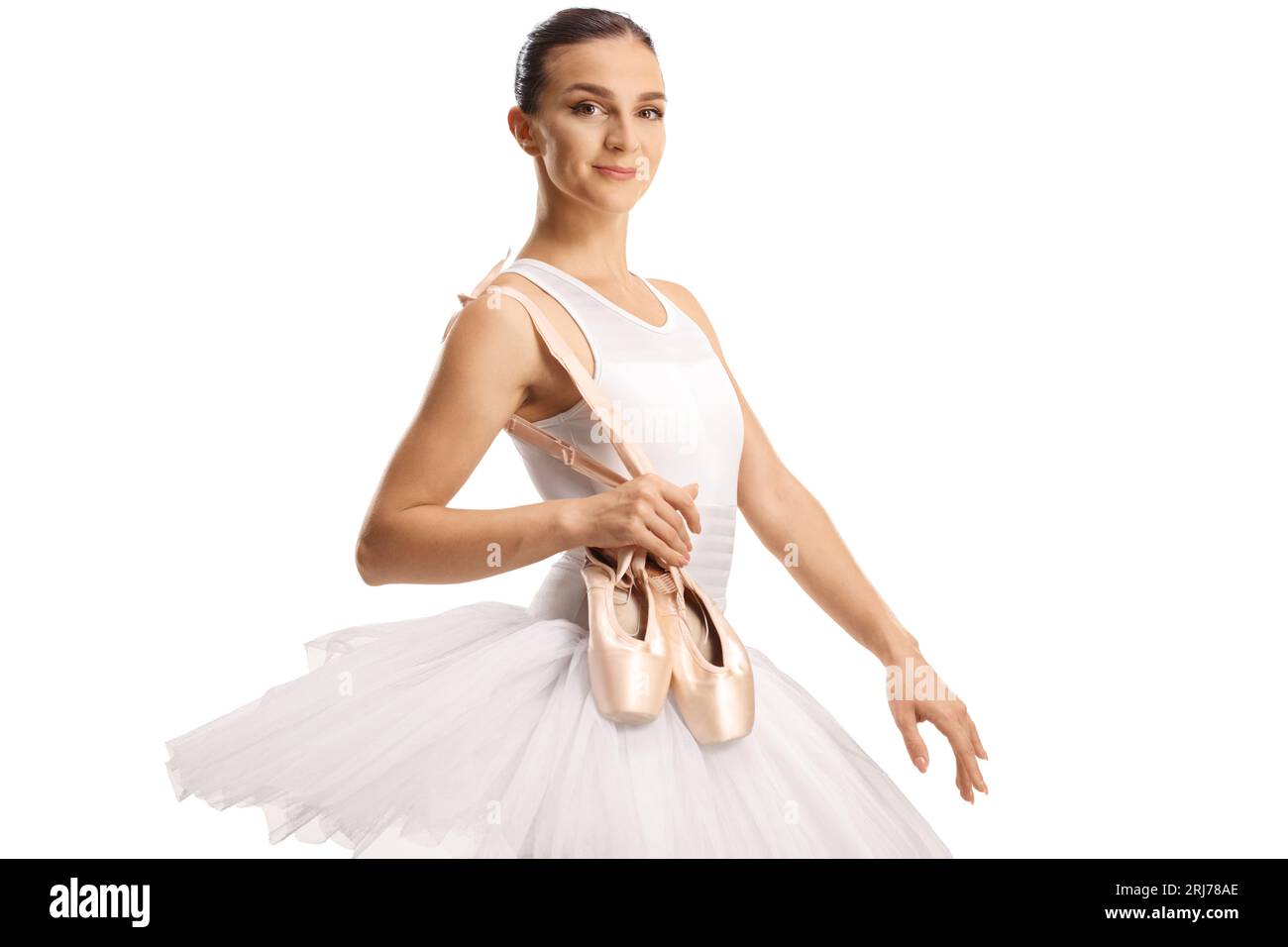 Ballet dancer holding her toe shoes and smiling isolated on white ...
