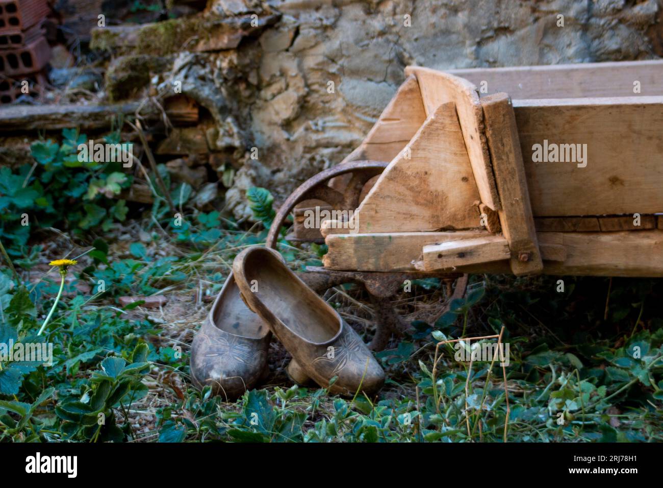 Rural scene, wooden clogs resting on a work wheelbarrow in a courtyard ...
