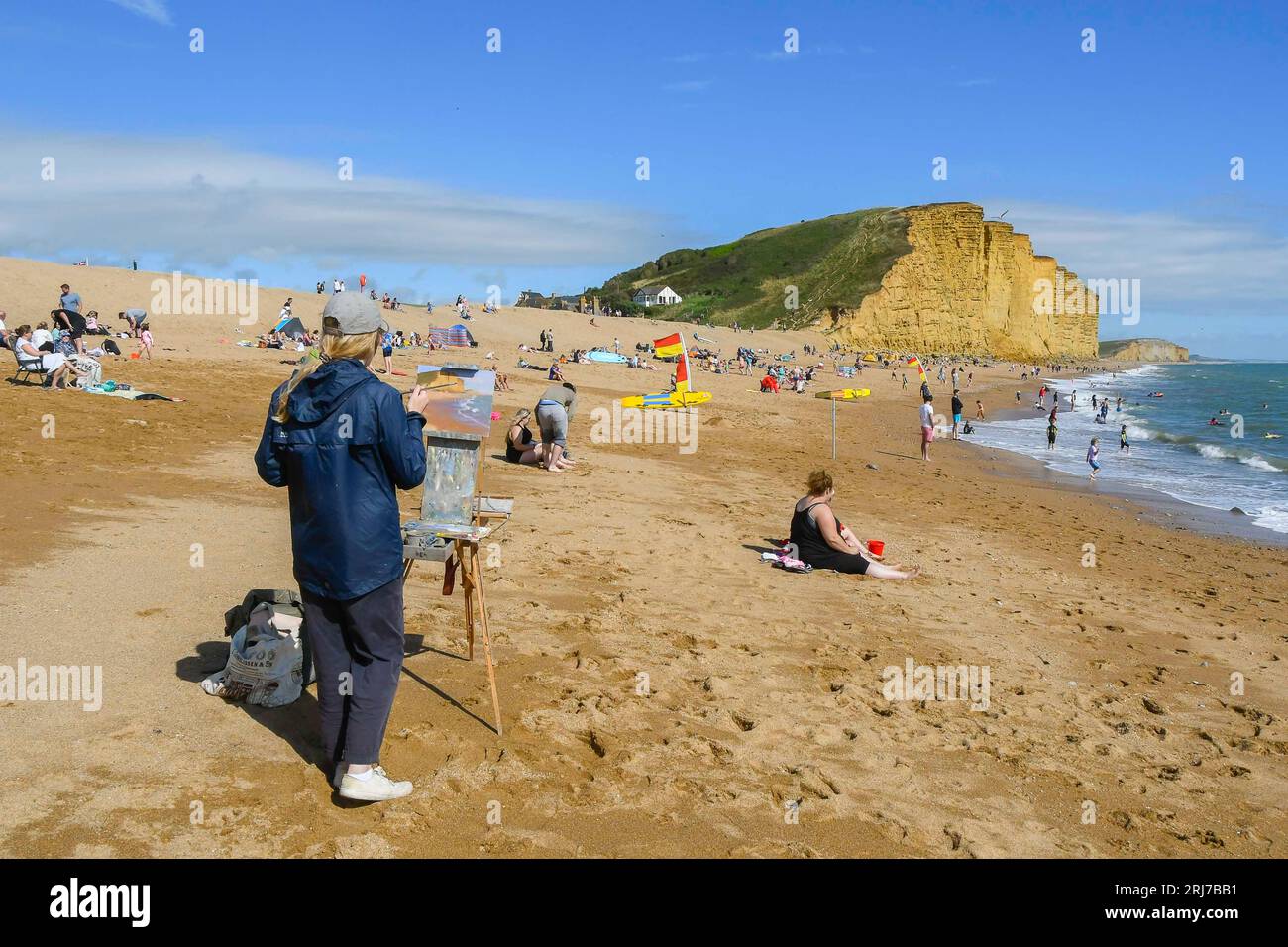 West Bay, Dorset, UK. 21st August 2023. UK Weather. An artist paints the cliffs and the beach as ...