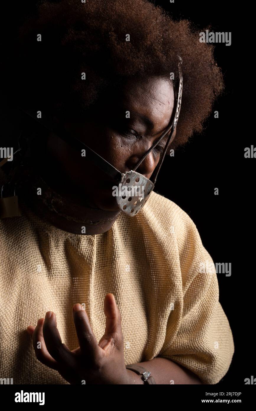 Portrait of a black woman wearing an iron mask on her face to represent ...