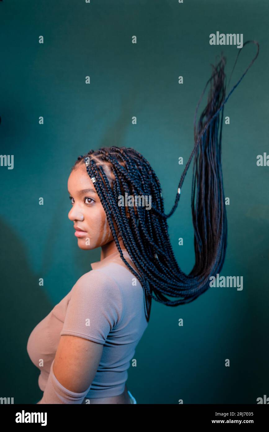 Beautiful young woman, sitting sideways, with braids of her hair flying ...