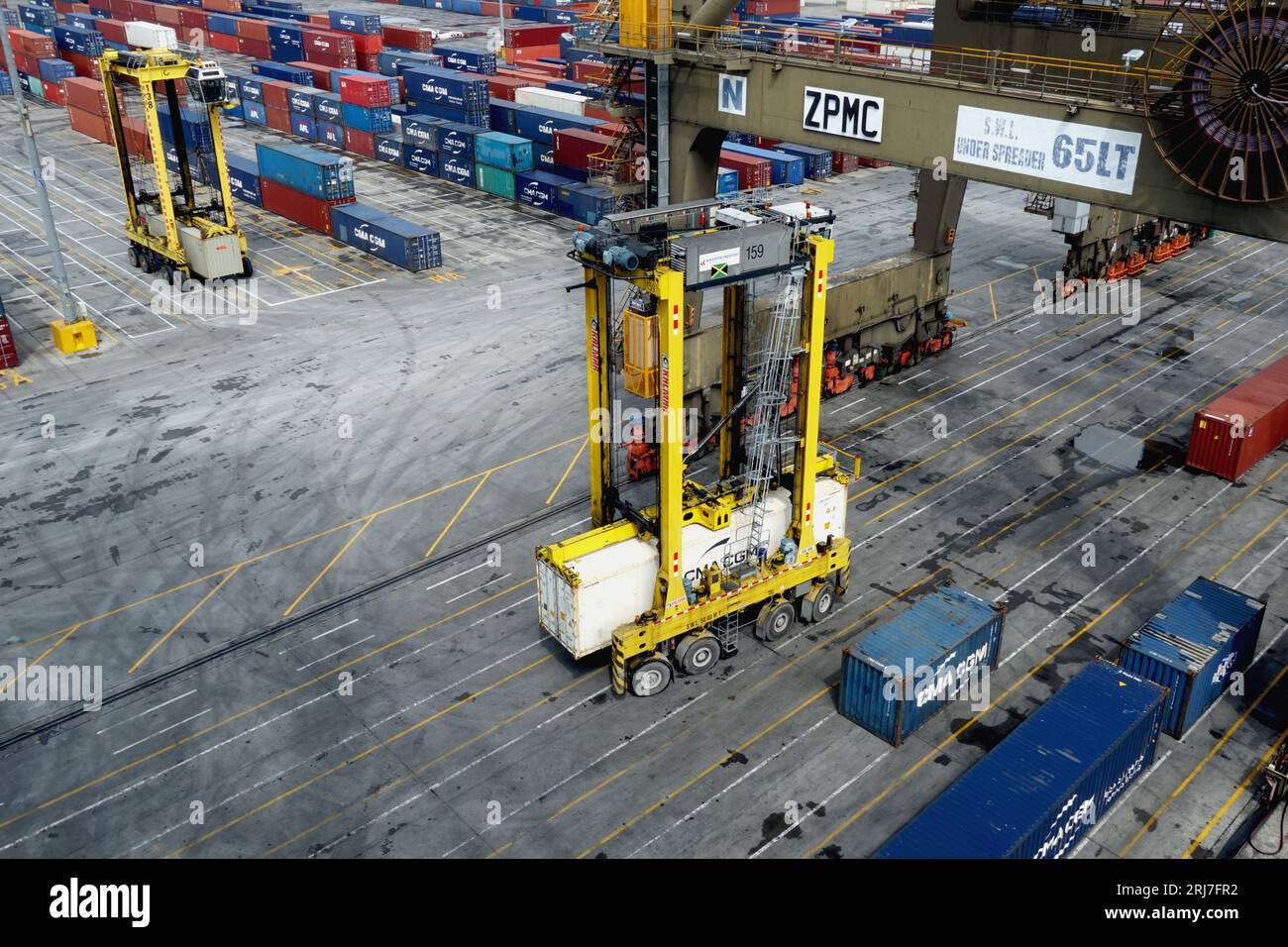 A yellow straddle carrier loaded with white reefer container in ...
