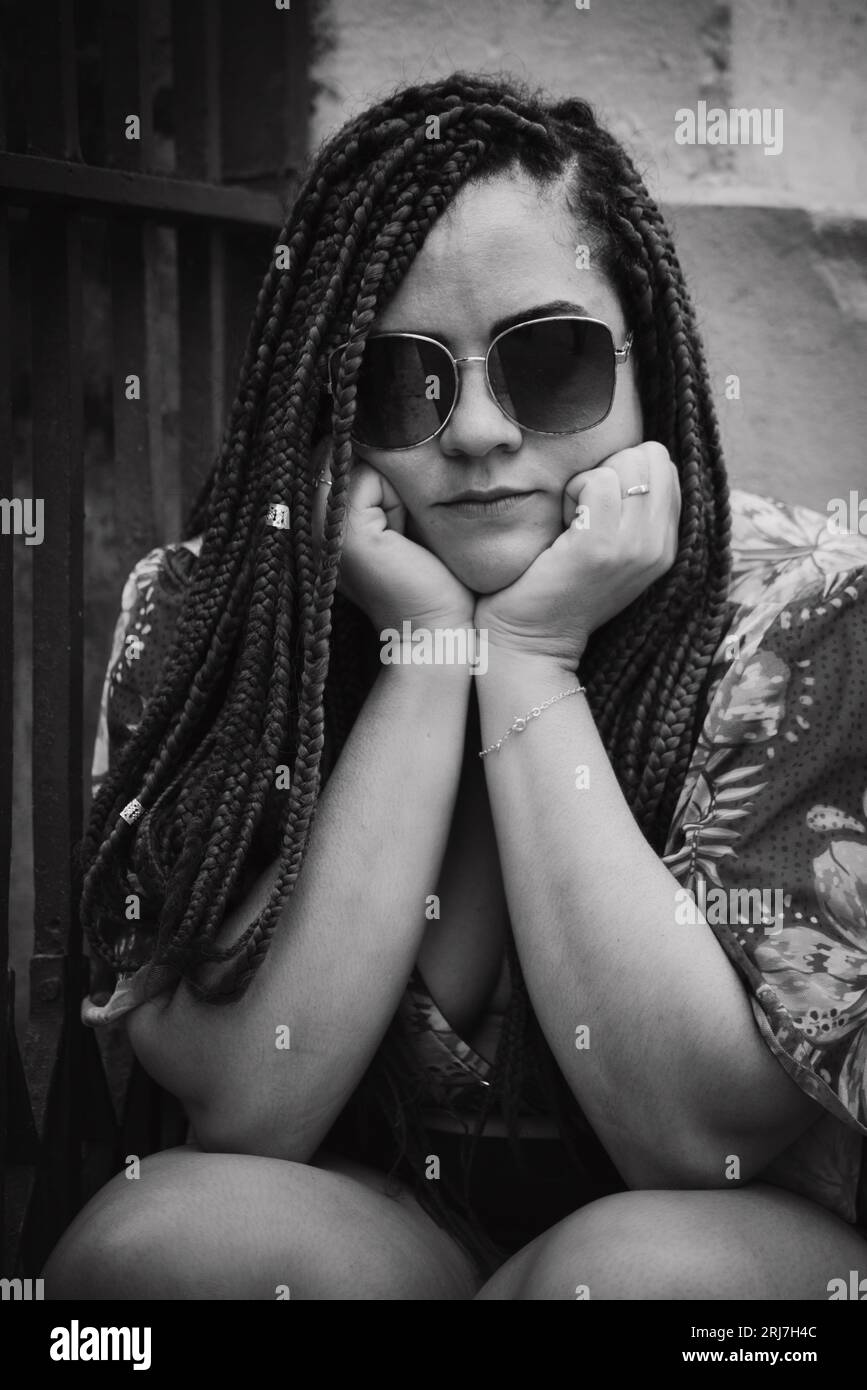 Black and white portrait of a woman wearing sunglasses crouching down ...
