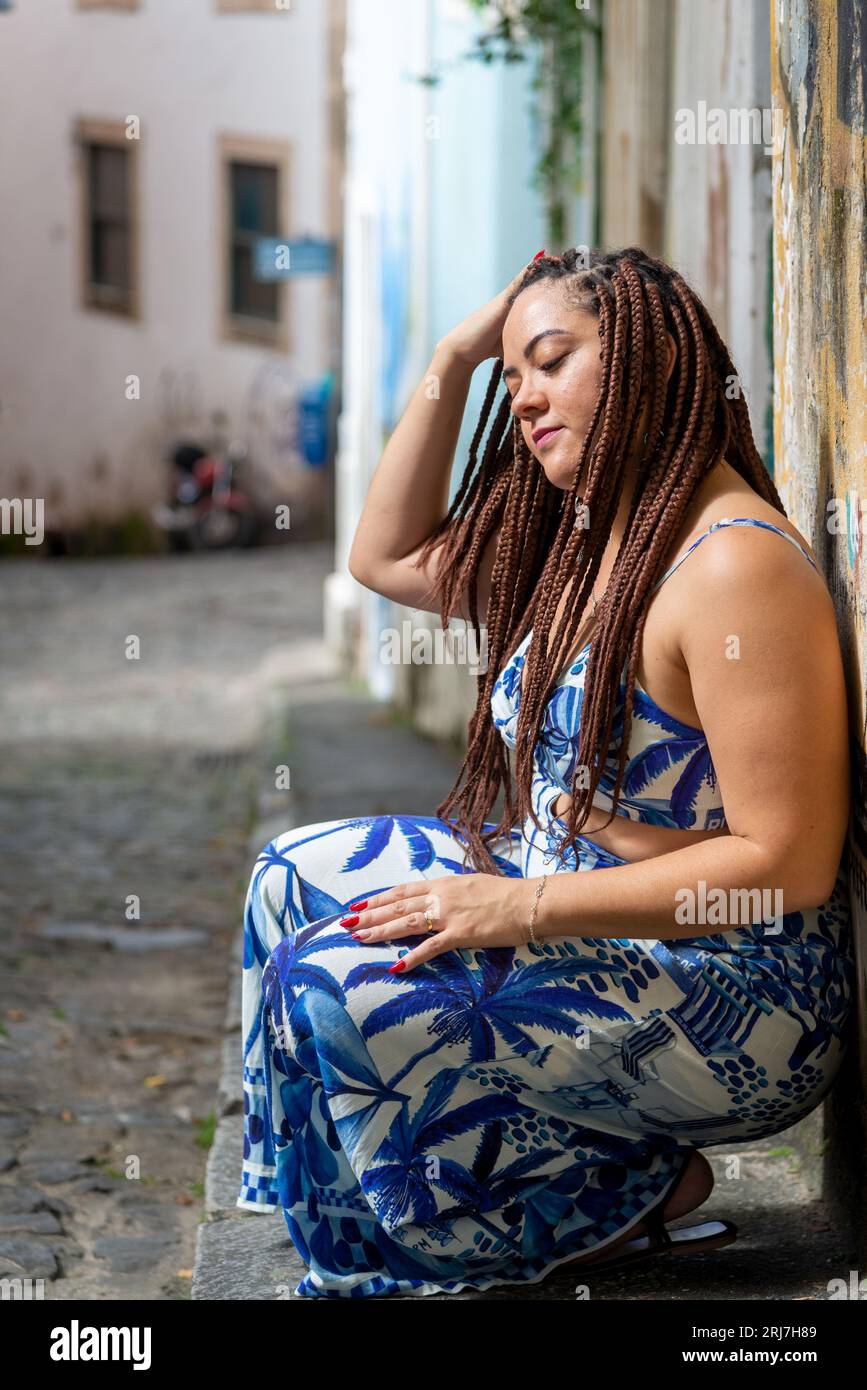 Portrait of a pretty woman crouching down and leaning against a wall in ...